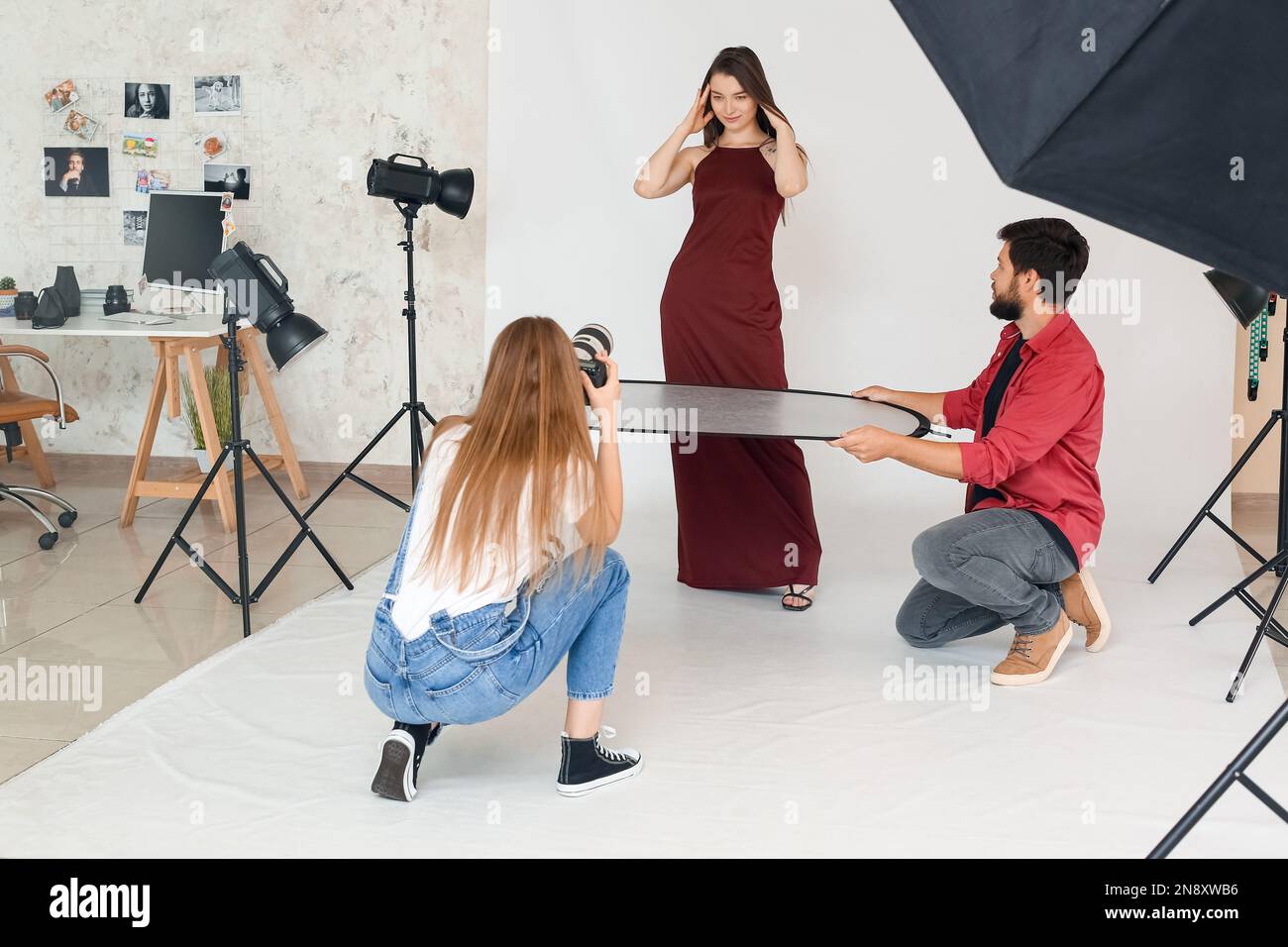 Female photographer and her assistant working with beautiful model in ...
