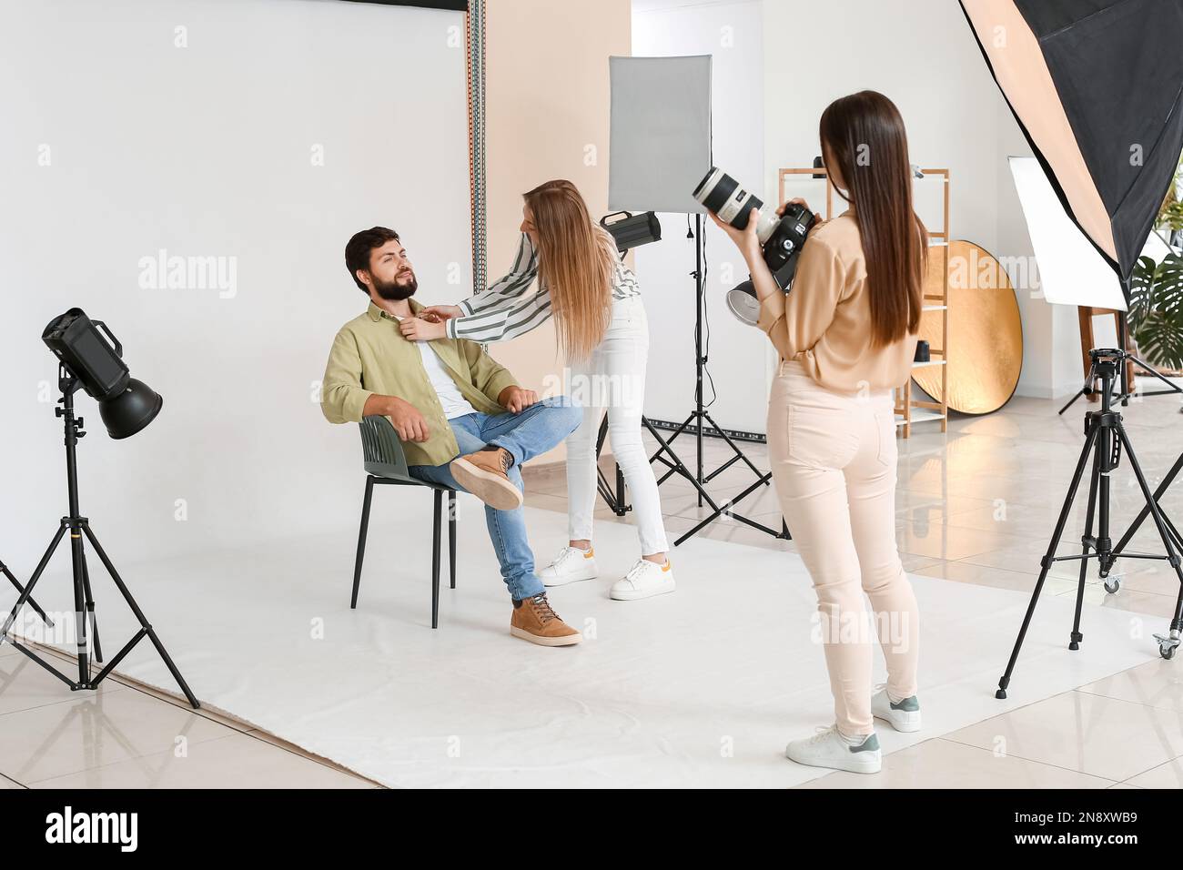 Female photographer and her assistant working with handsome model in ...