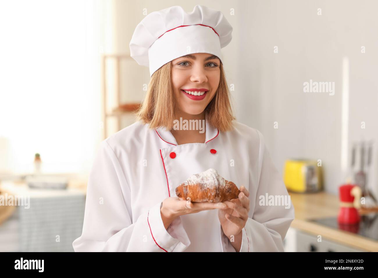 Female baker with tasty croissant in kitchen Stock Photo - Alamy