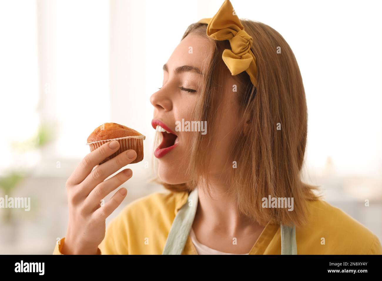 Female baker eating tasty cupcake in kitchen, closeup Stock Photo - Alamy