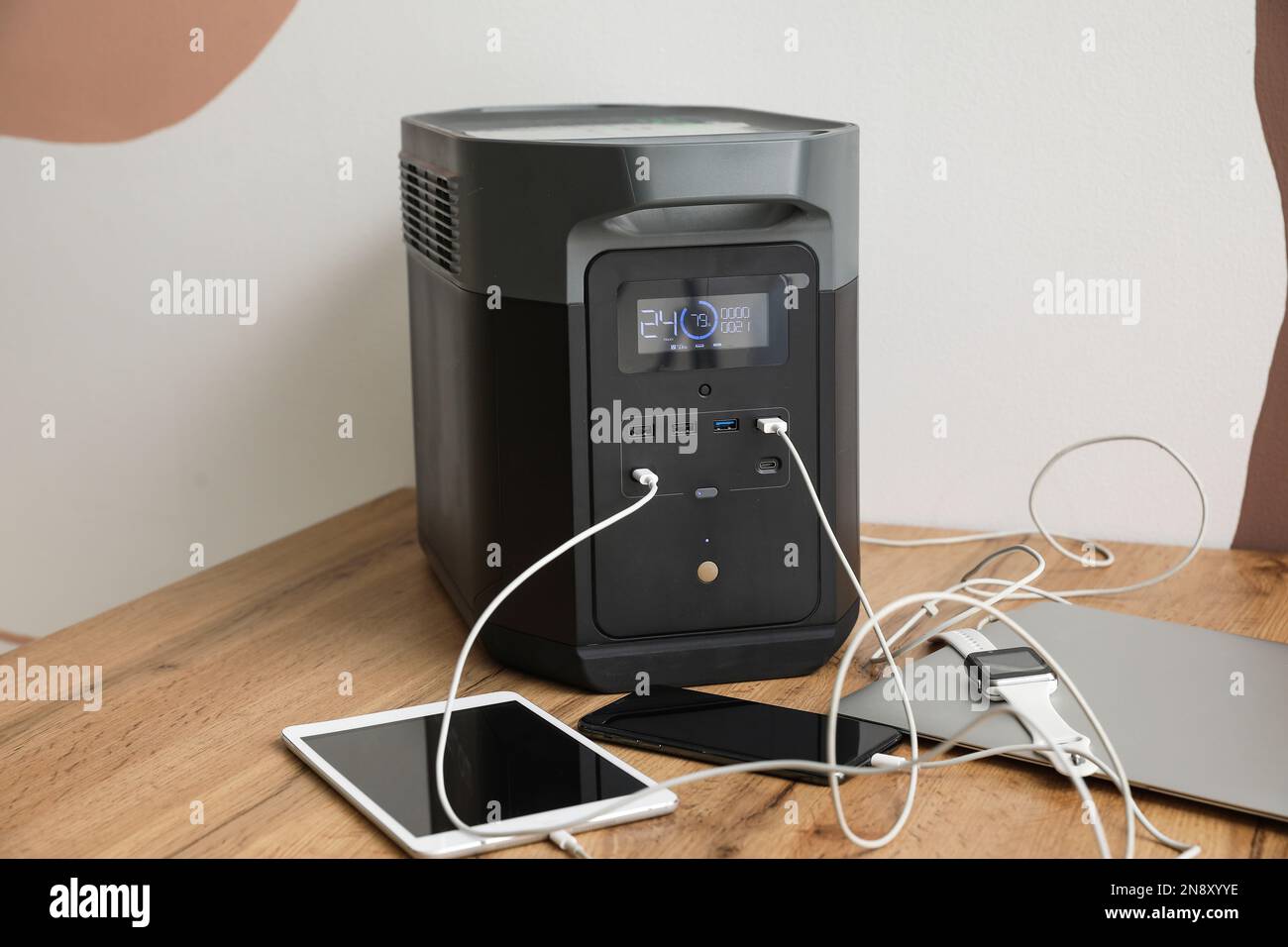 Portable power station charging gadgets near wall Stock Photo - Alamy