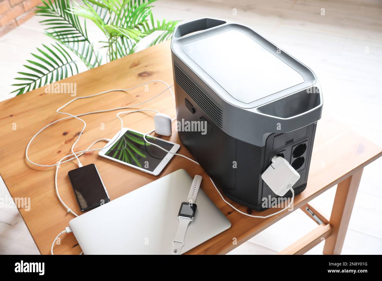 Portable power station charging gadgets on table in room Stock Photo ...