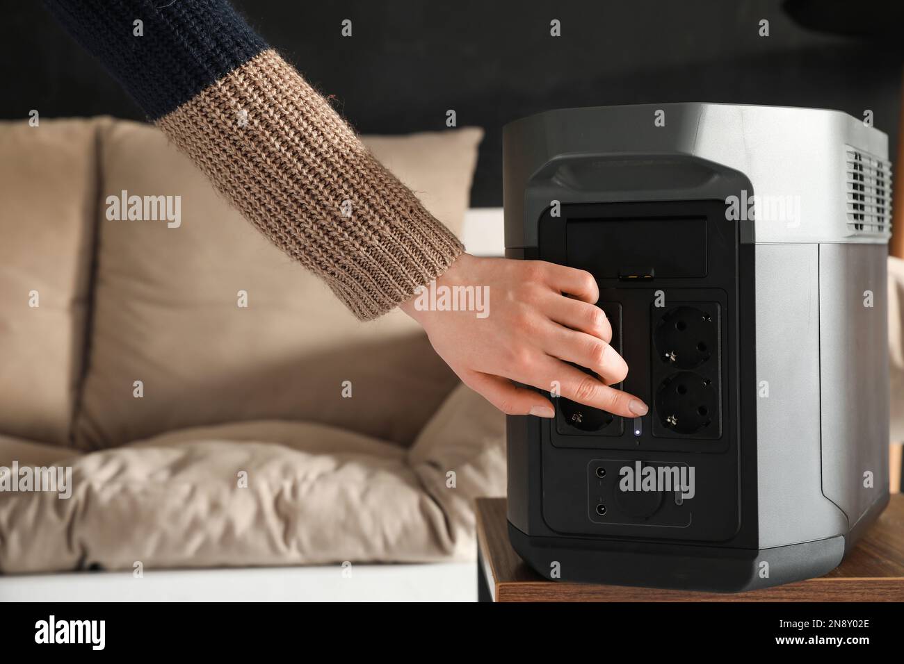 Woman turning on portable power station at home, closeup Stock Photo ...