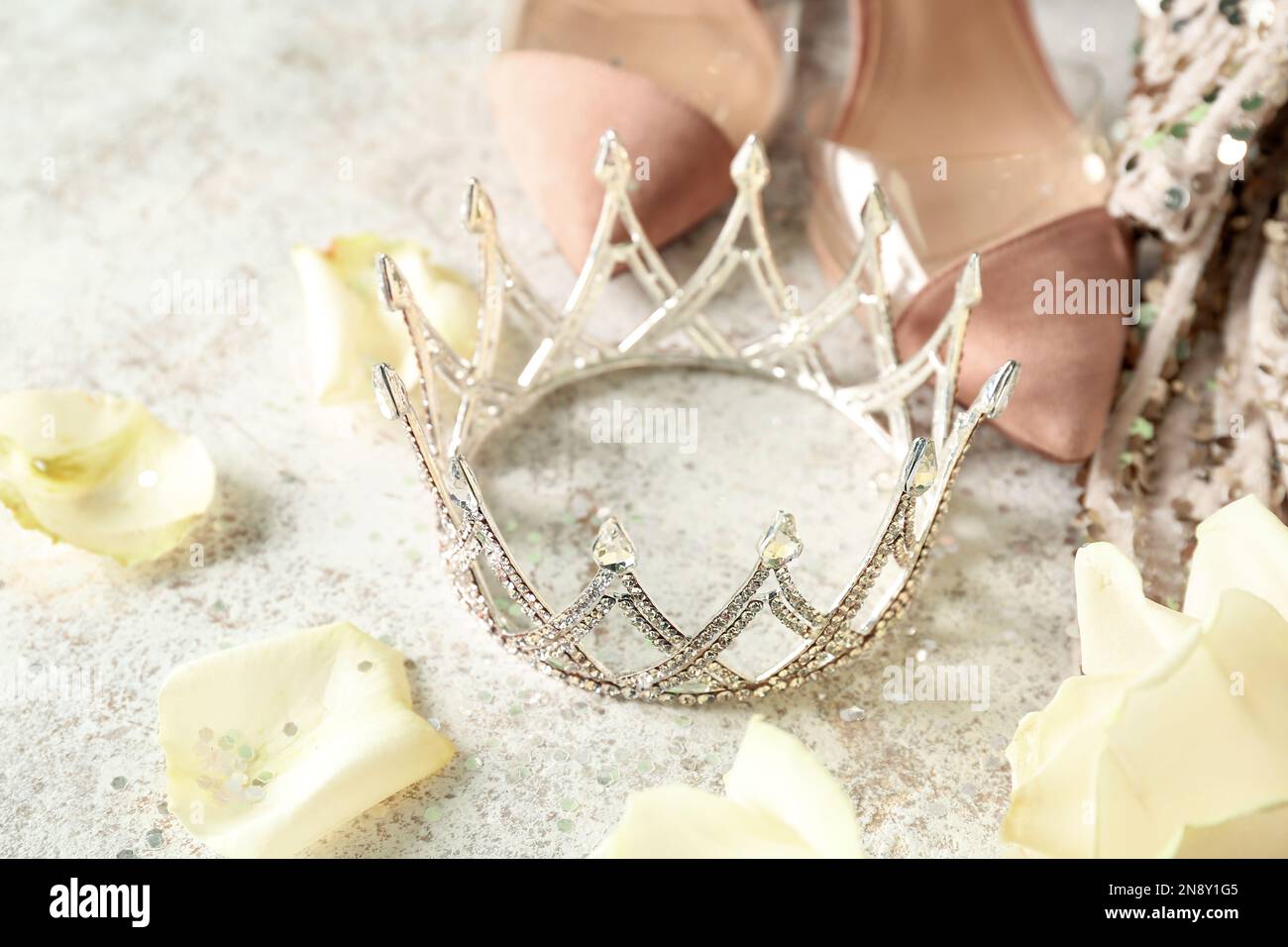 Beautiful tiara with rose petals on grunge table, closeup. Prom concept ...