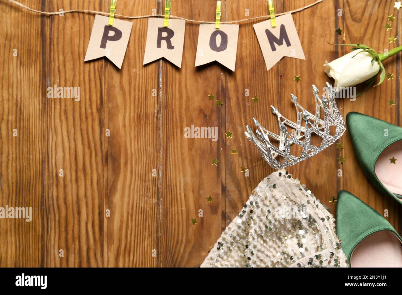 Flags with word PROM, tiara, rose, dress and heels on wooden background ...