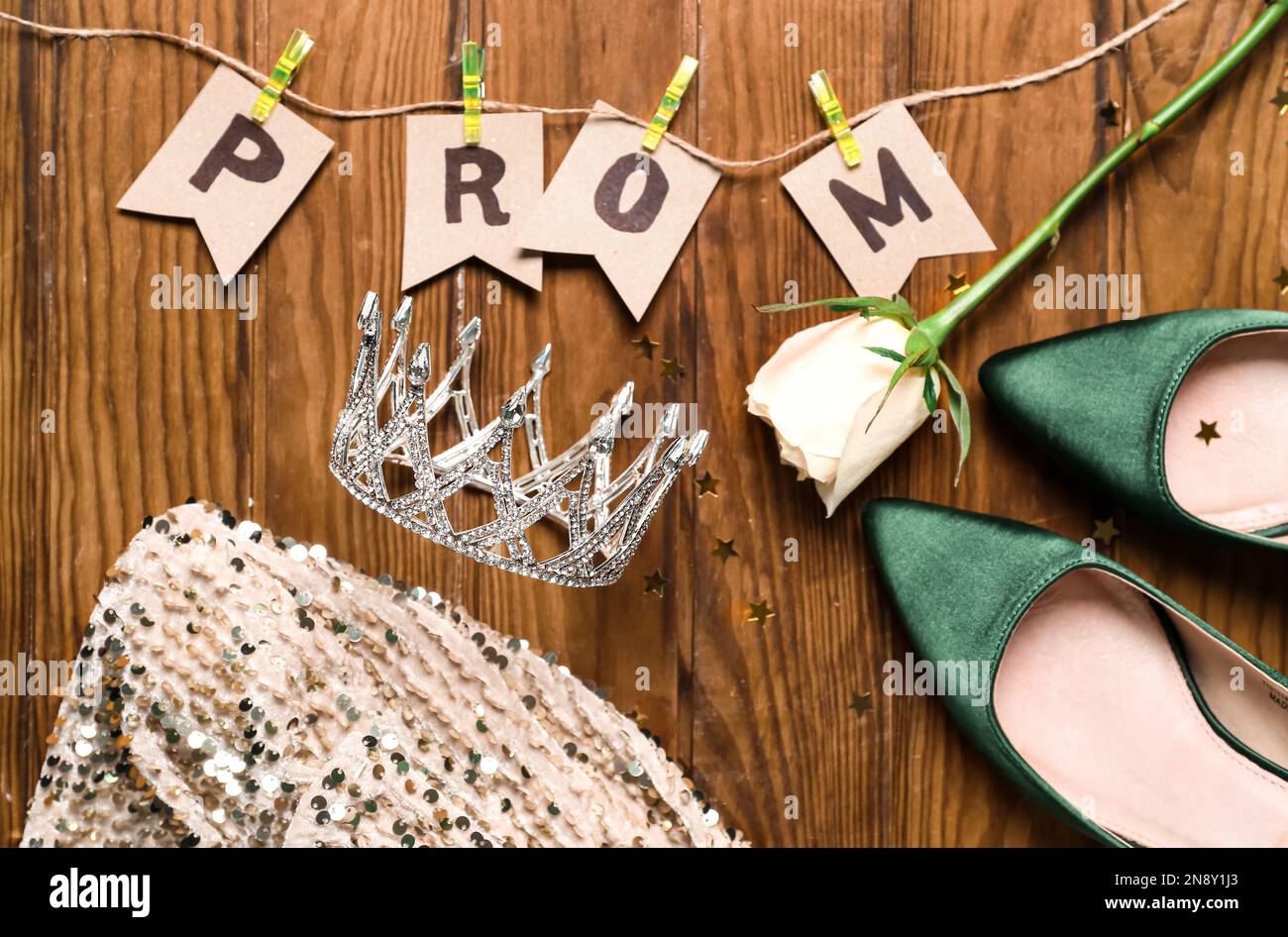 Flags with word PROM, tiara, rose, dress and heels on wooden background ...
