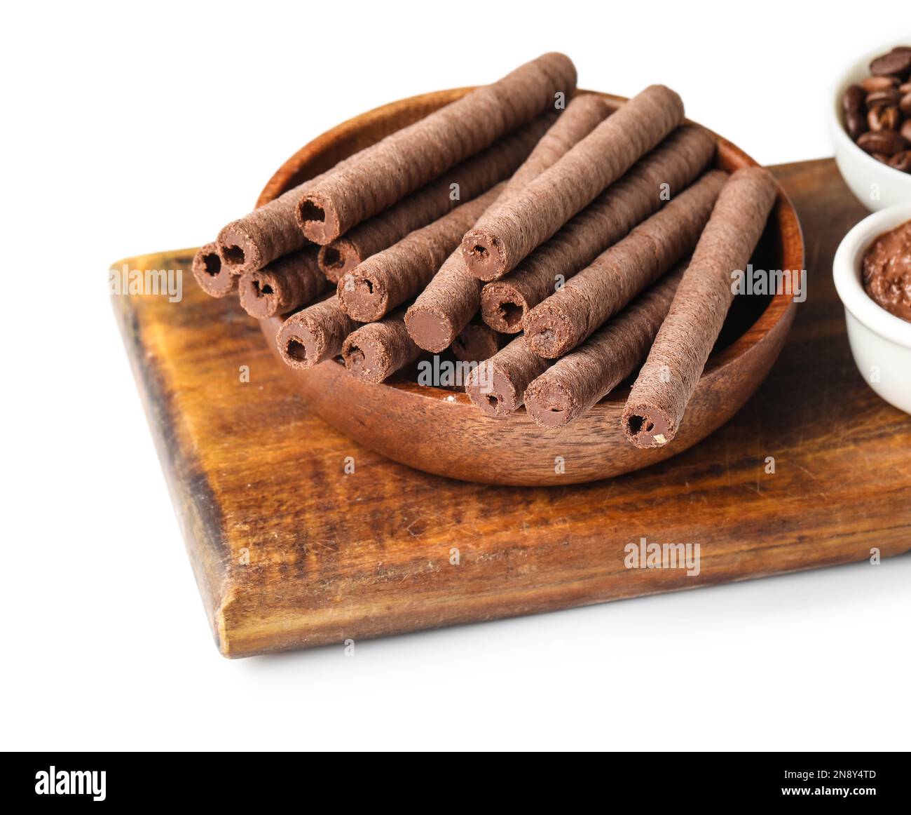 Board with bowl of delicious chocolate wafer rolls isolated on white ...