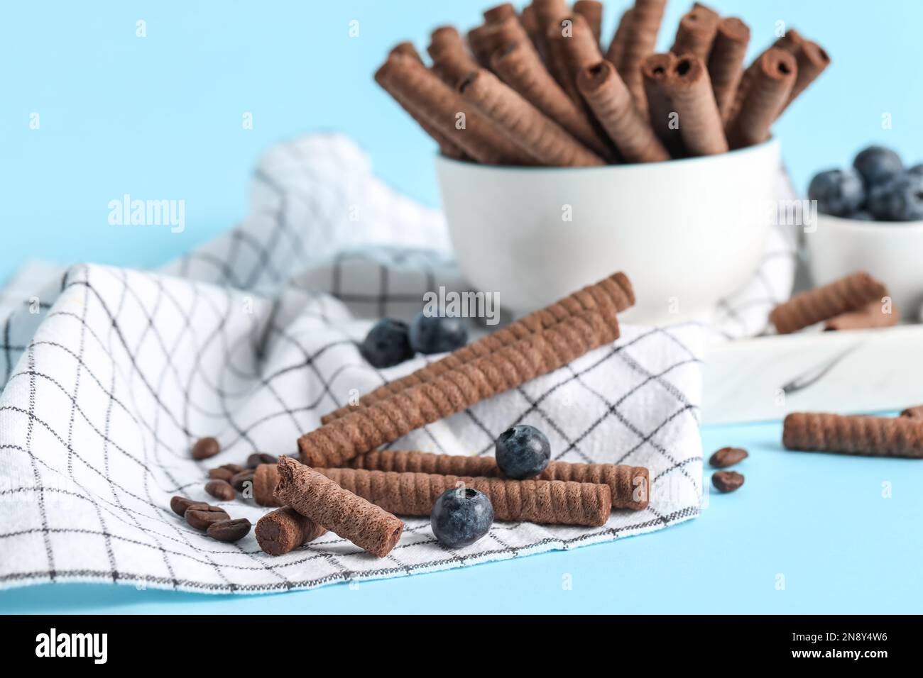Delicious chocolate wafer rolls and blueberries on blue background ...