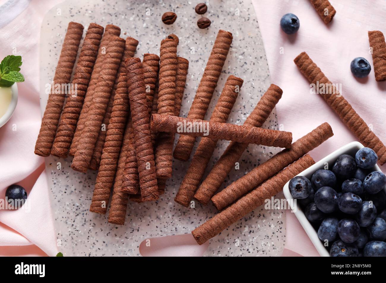 Board with delicious chocolate wafer rolls, blueberries and coffee ...