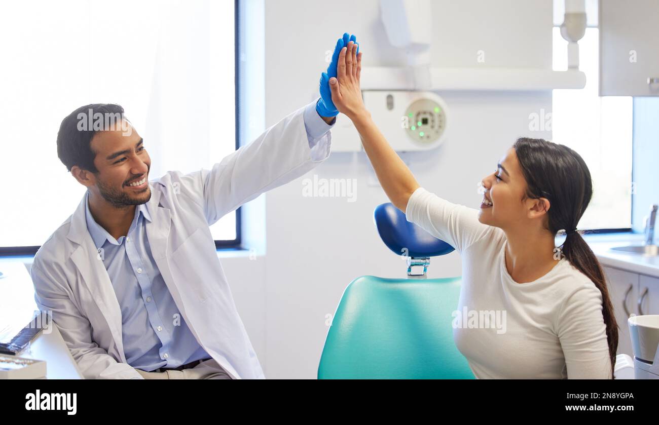 Go and get your smile on. a young woman giving her dentist a high five ...