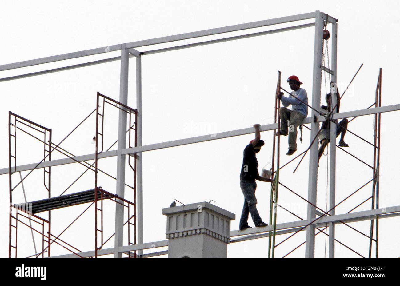 Workers build the frame of a giant billboard in Jakarta, Indonesia ...