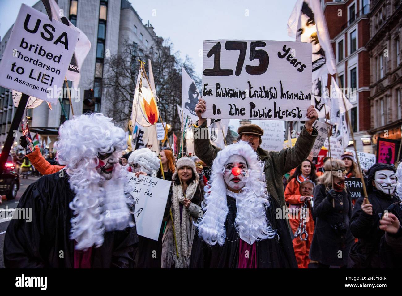 Protesters in costumes hold placards during the Julian Assange ...