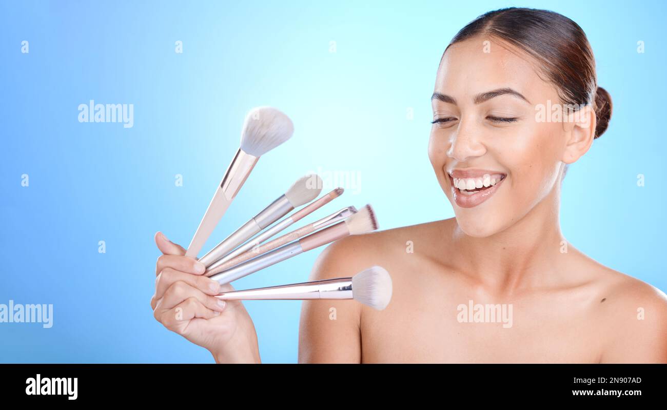 Woman, brushes and smile for makeup, cosmetics or beauty against a blue ...