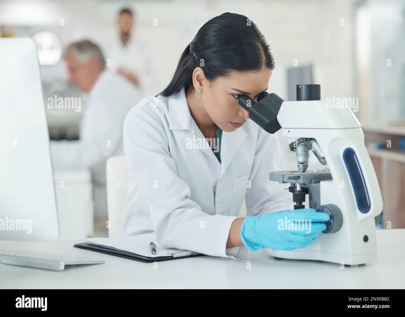 Using refined scientific methods in her analysis. a young scientist using a microscope in a lab ...