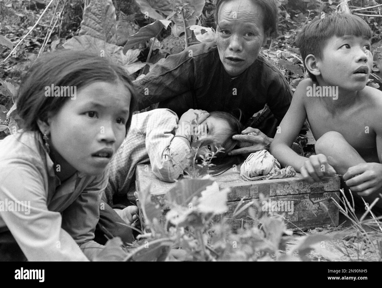 A Vietnamese mother huddles over her youngest child while her other ...