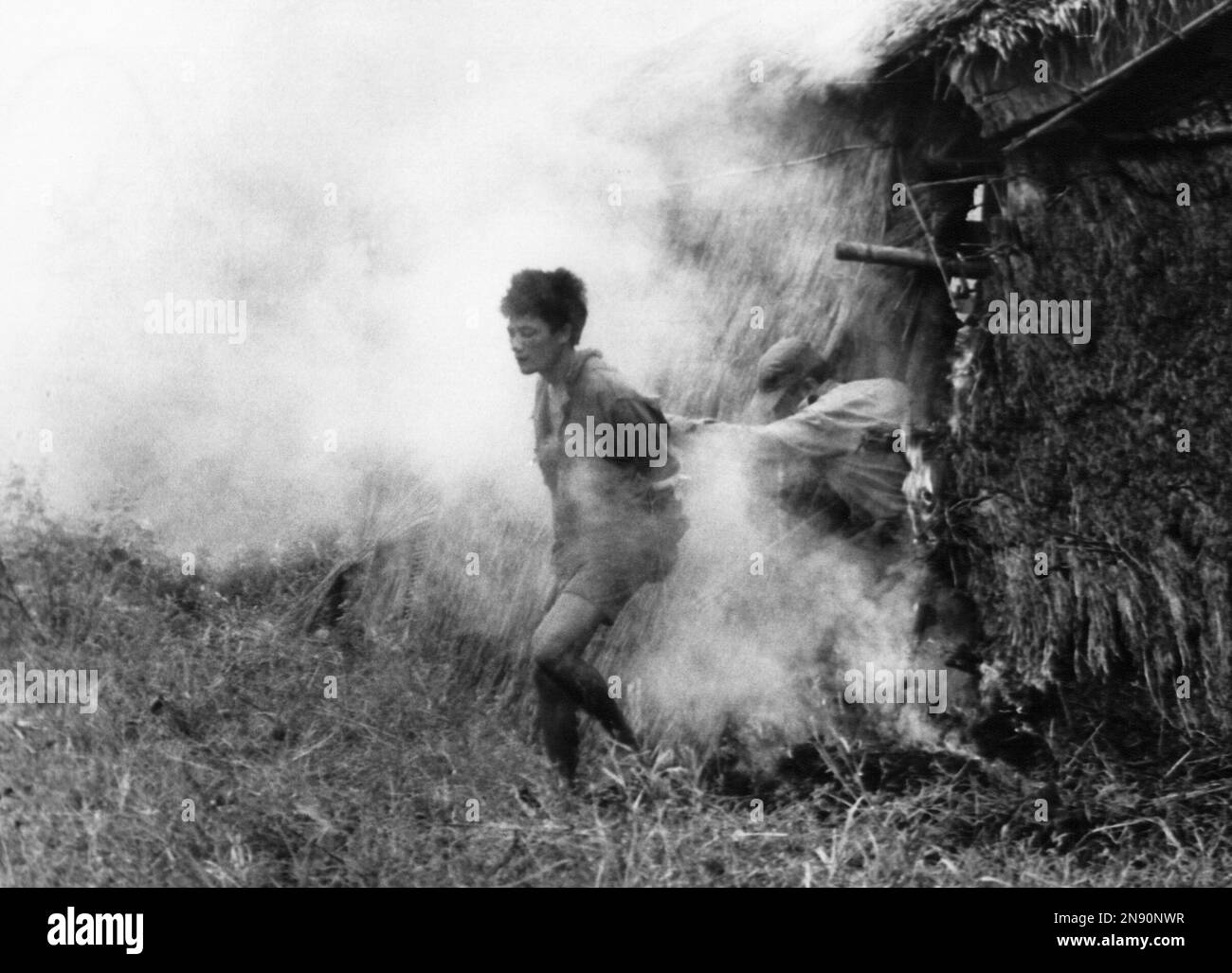 A South Vietnamese serviceman pushes a Viet Cong suspect from a burning ...