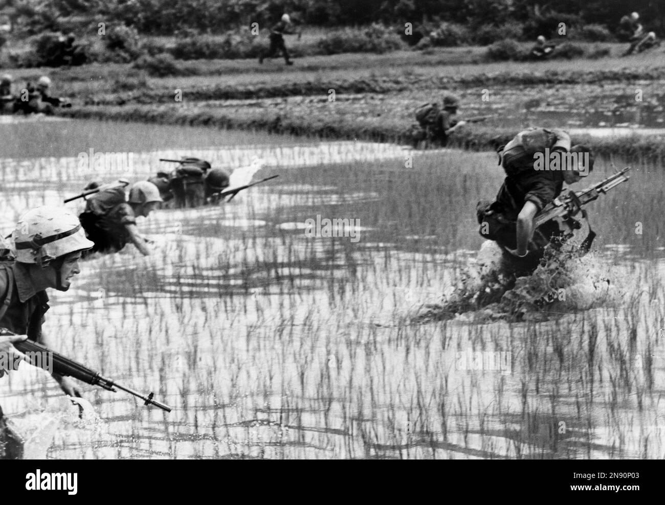 U.S. Marines wade through water and mud of flooded rice paddies during ...
