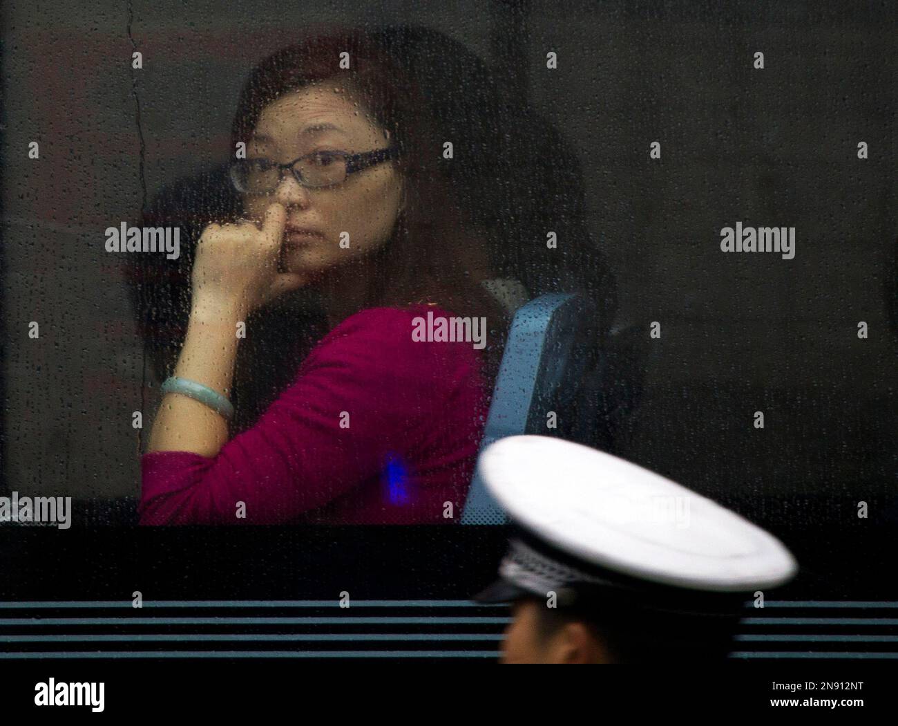 A woman looks out from a bus window as a policeman directs a traffic on ...