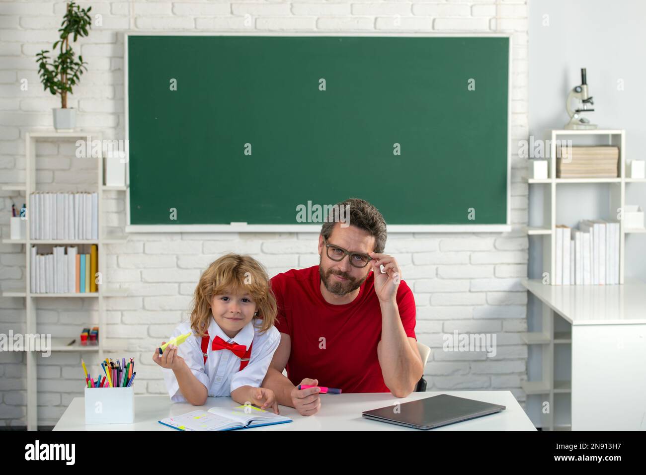 Elementary school boy in classroom on lesson. Teacher explaining to ...