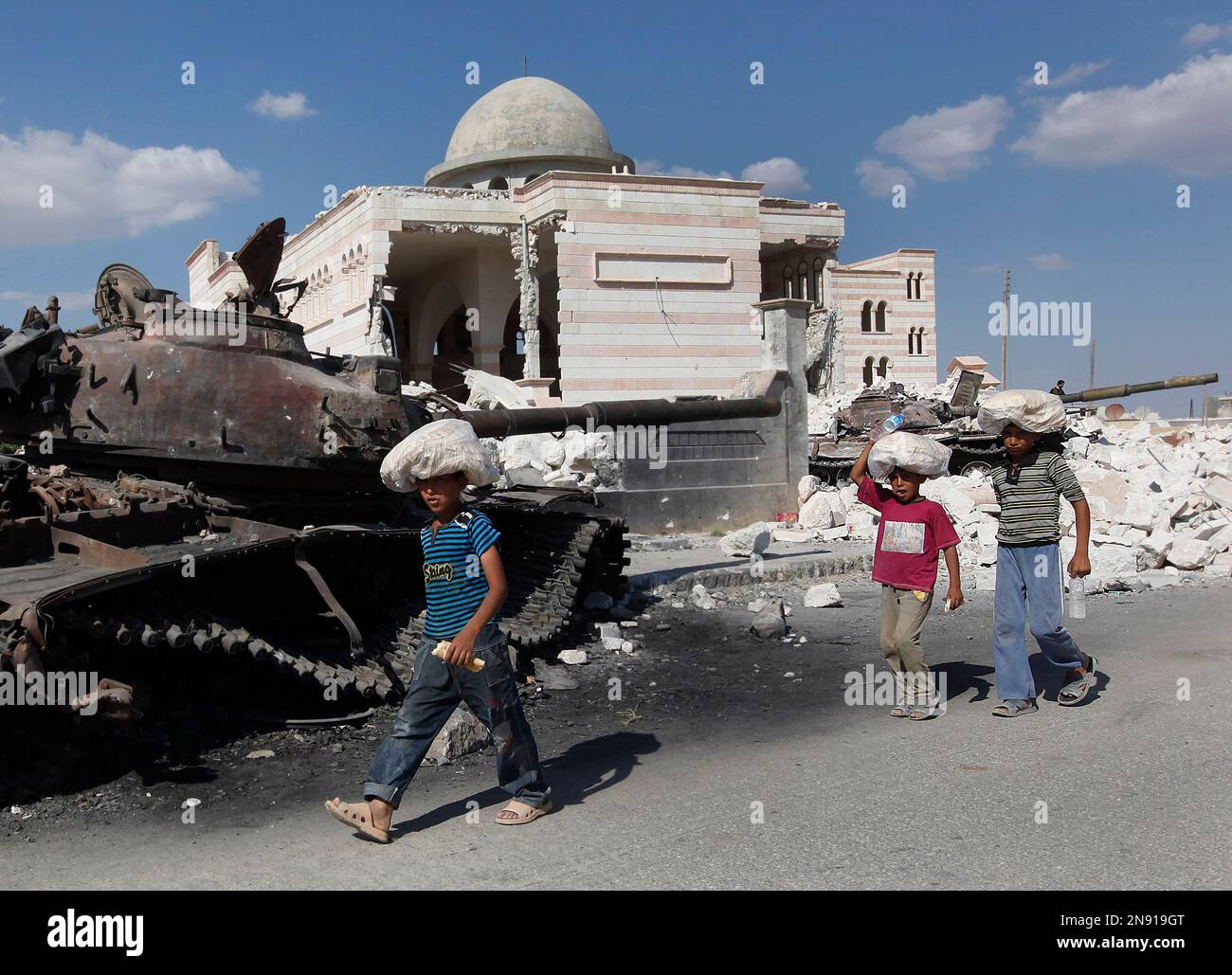 Syrian boys carry loaves of bread on their heads as they walk by a ...