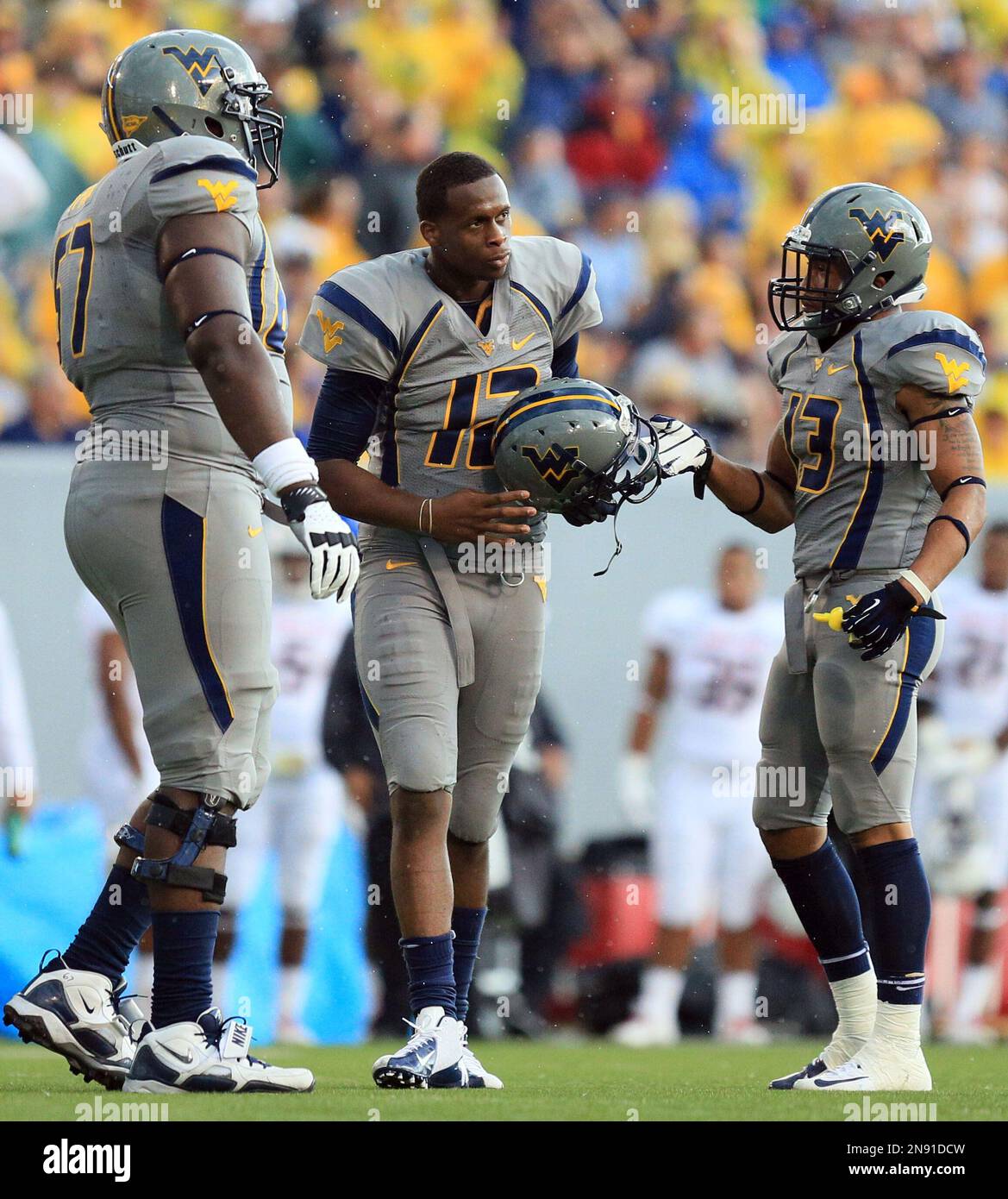 West Virginia quarterback Geno Smith (12) is handed his helmet back ...