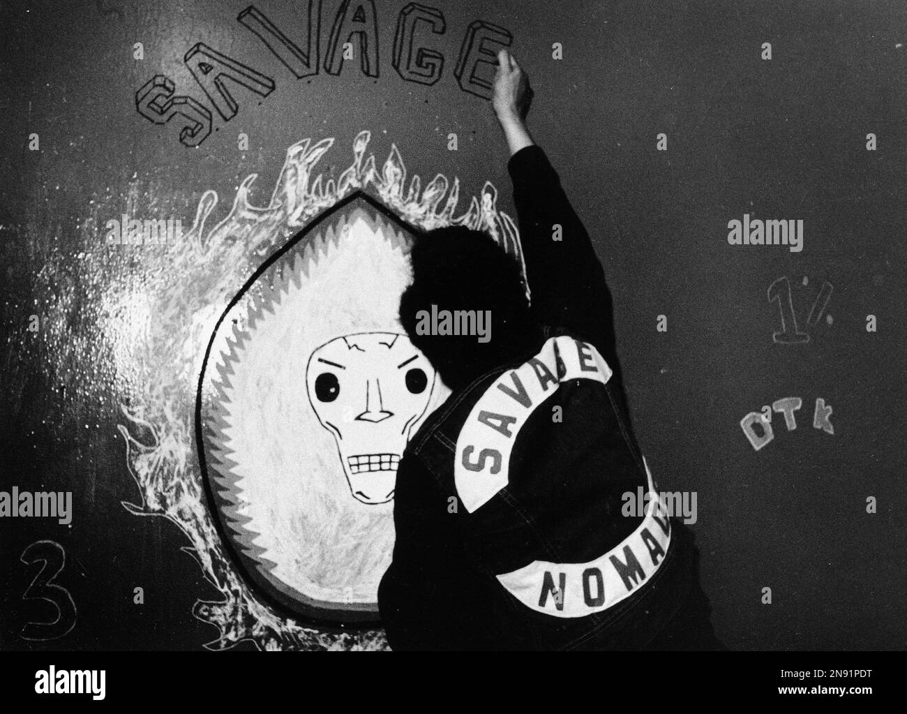 A South Bronx gang leader reaches to touch up a letter over his group's ...