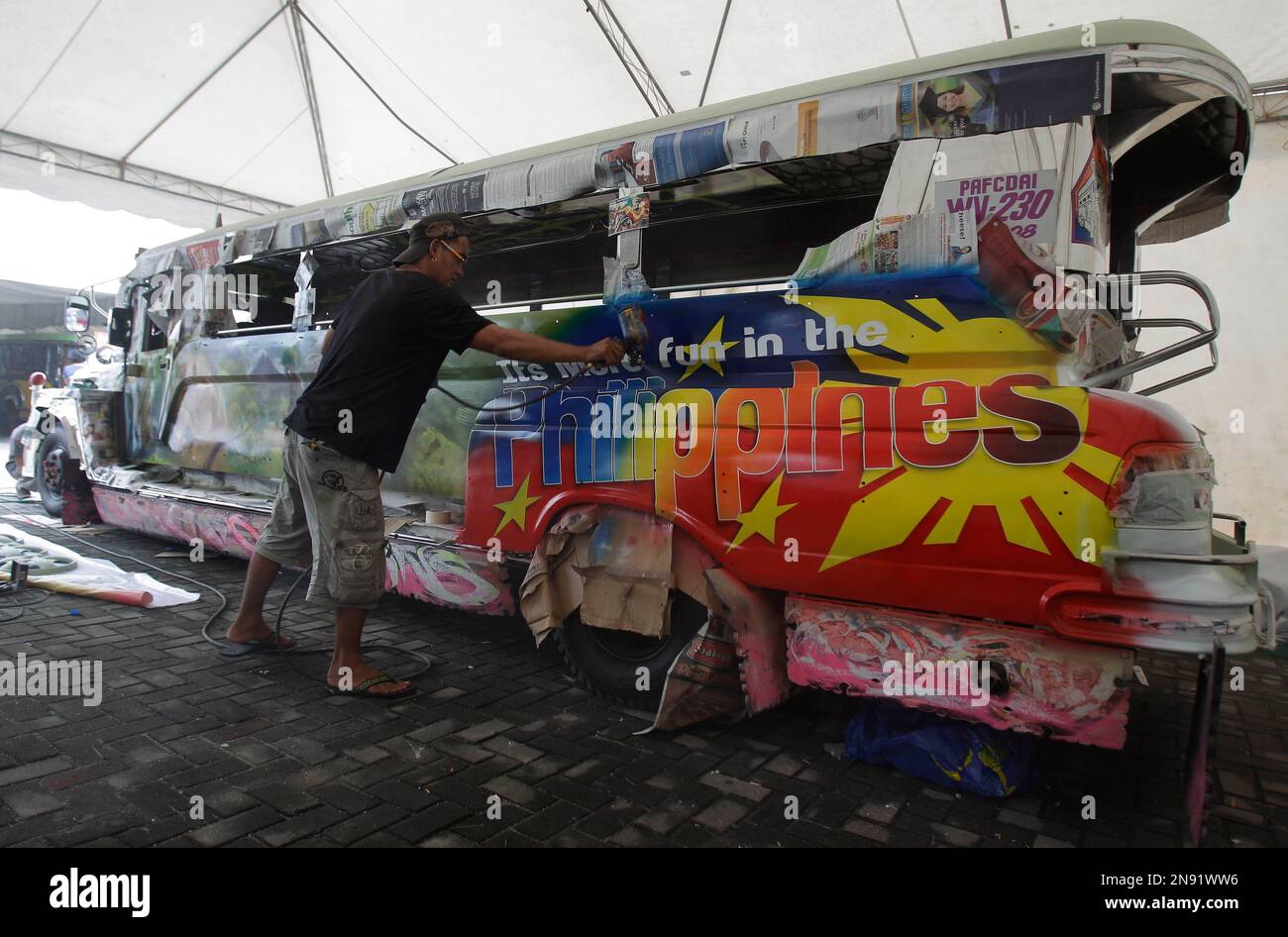 A Filipino jeepney artist sprays paint on a passenger jeepney during a ...