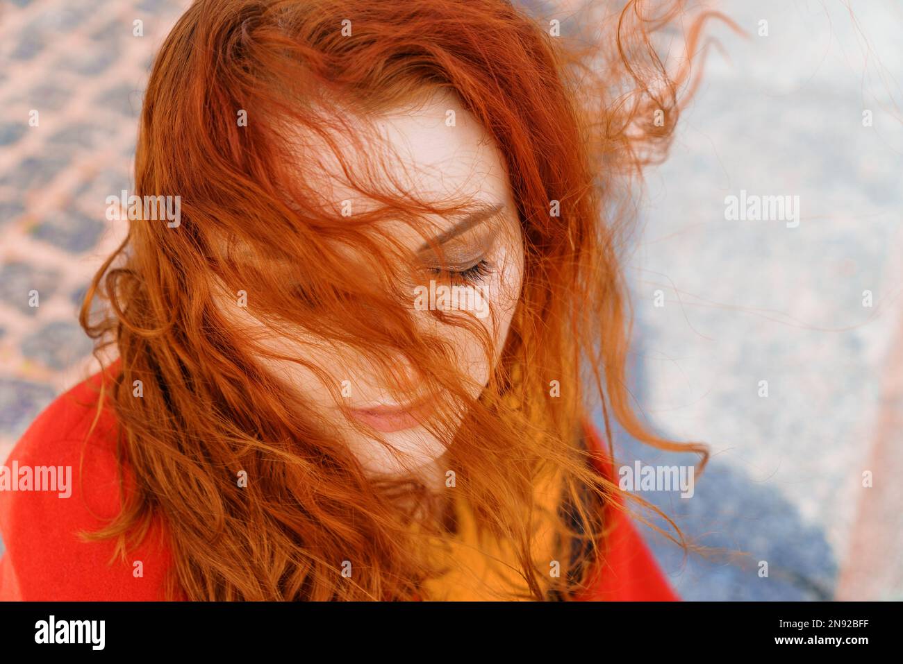 Close-up portrait young caucasian woman with red curly hair in a red ...