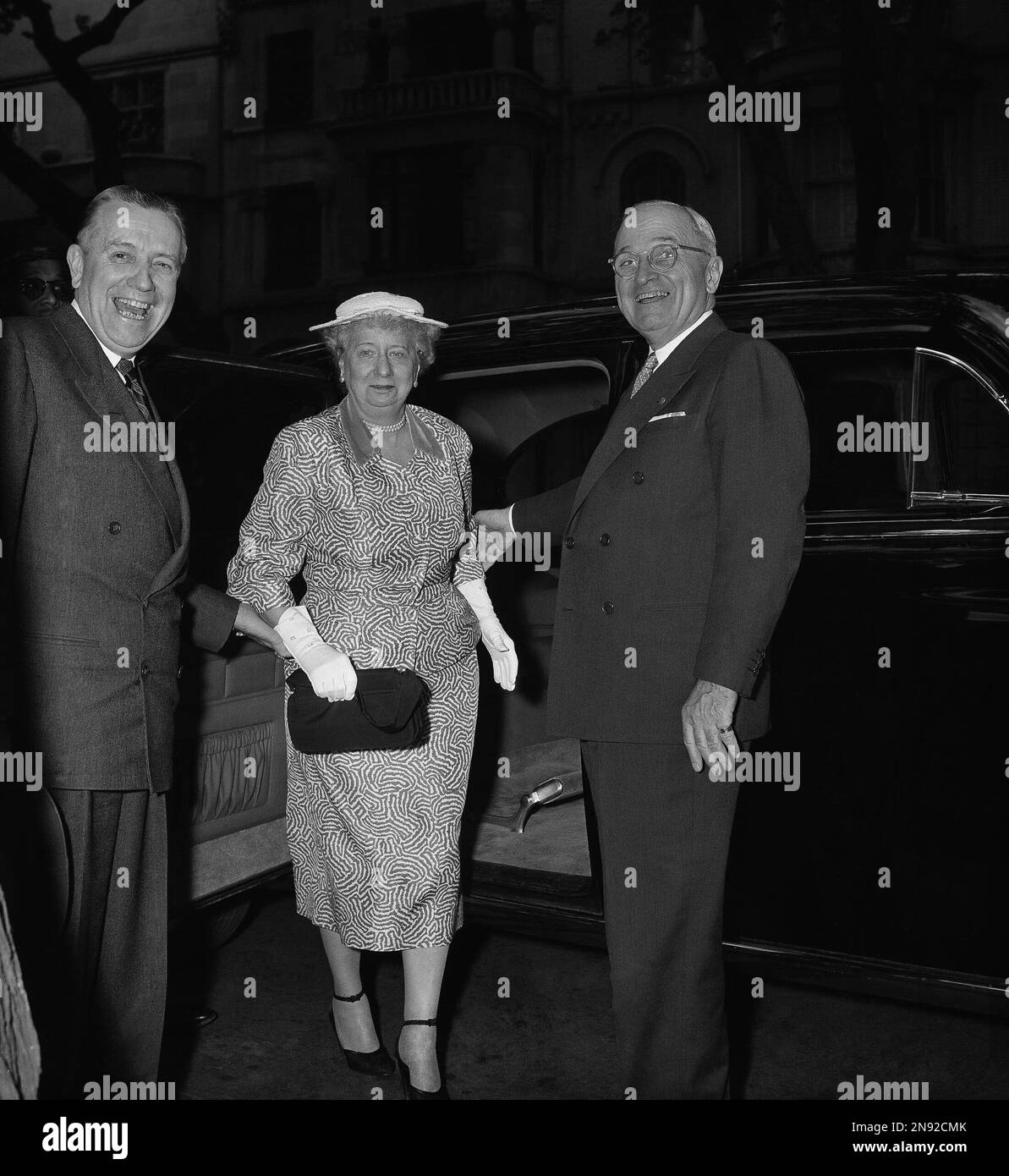President Harry S. Truman helps his wife, Bess, from auto is as they ...