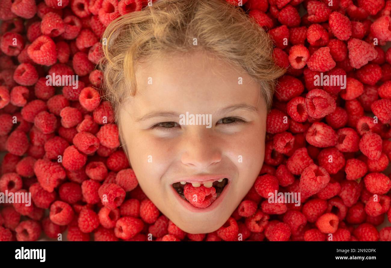 Funny kids face near raspberry background. Raspberry in kids mouth ...