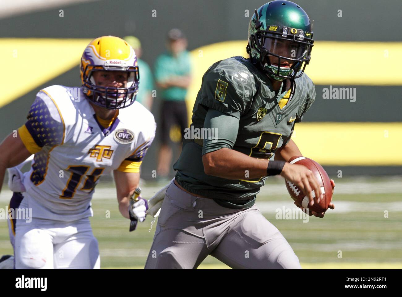Oregon quarterback Marcus Mariota, right, gains yardage against ...