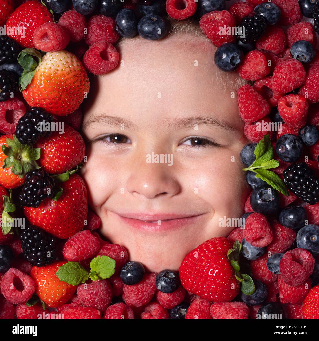 Fruits for kids. Child face with berries mix of strawberry, blueberry ...