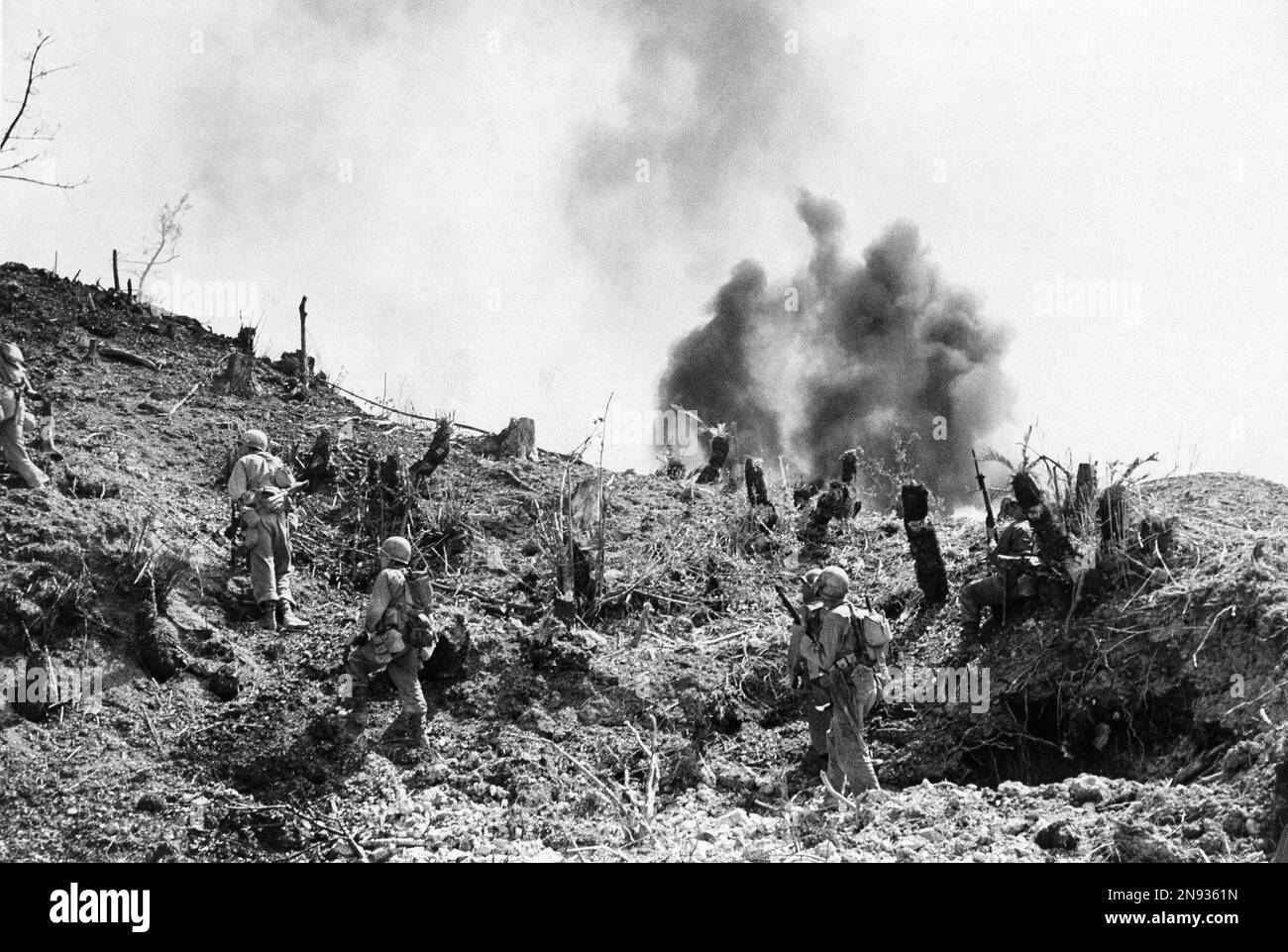 Troops advance on skyline ridge, ducking as Japanese grenades explode ...