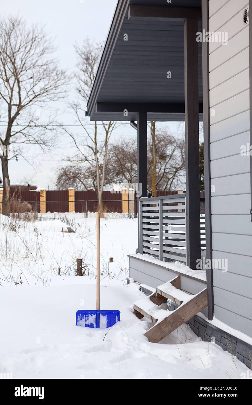 Snow-covered courtyard near the house with a shovel stuck in the snow ...