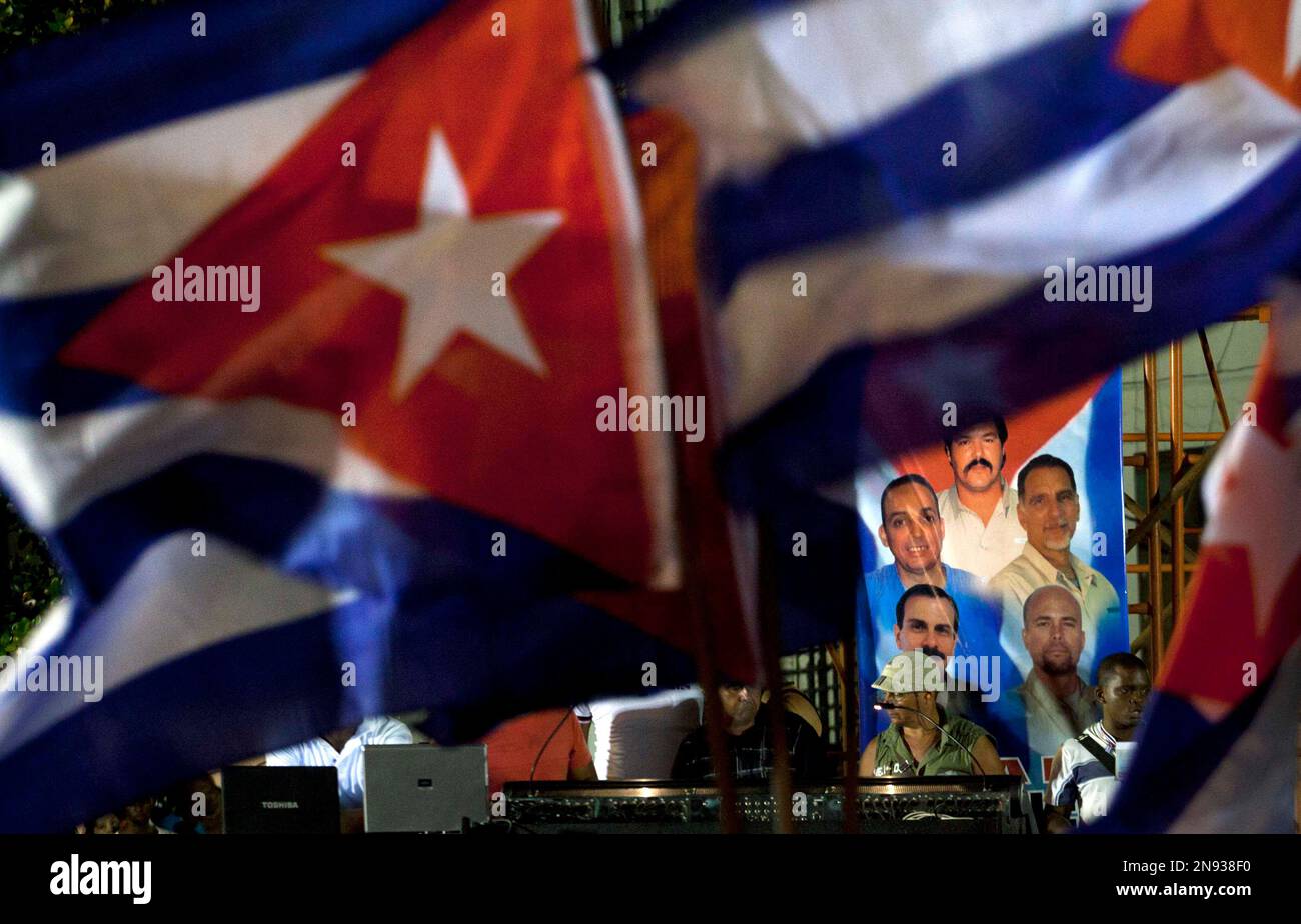 Cuban flags fly near to a poster of photographs of five Cuban ...
