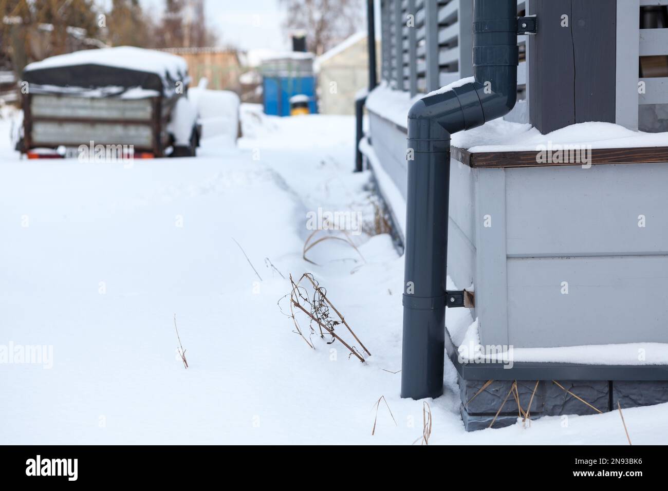 Drainage plastic pipe covered with snow against the background of ...