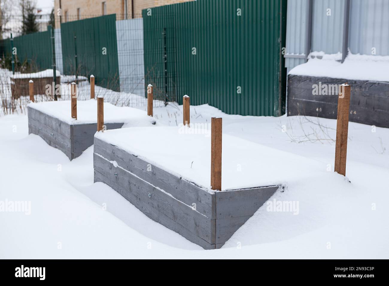 A lot of snow is in the high garden-beds. Wooden walls raised up over ...