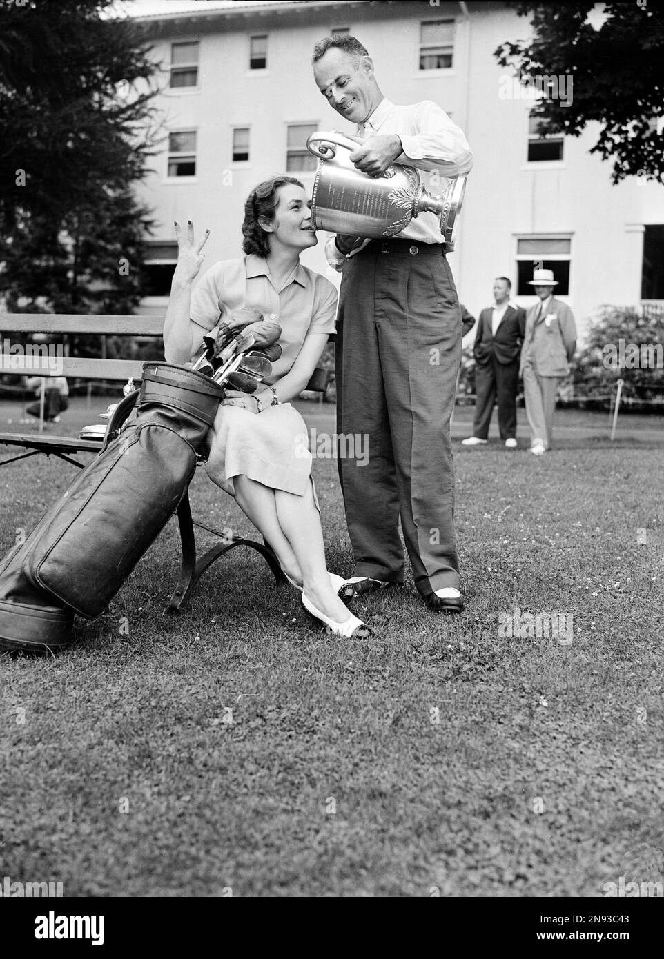 Golfer Denny Shute is shown with his wife Hettie, as she drinks from ...