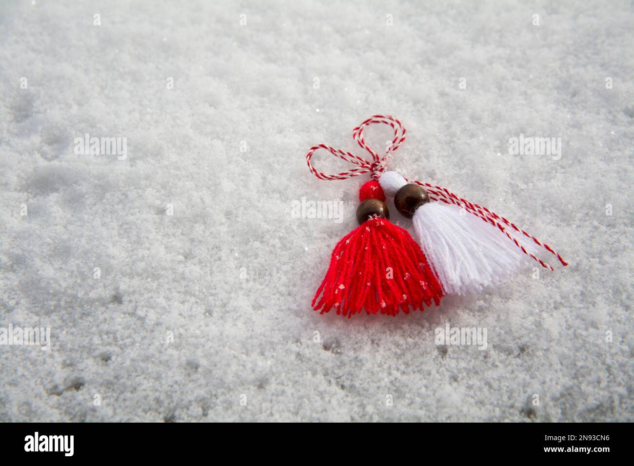 Closeup of a red and white martenitsa (martisol) with wooden beads ...