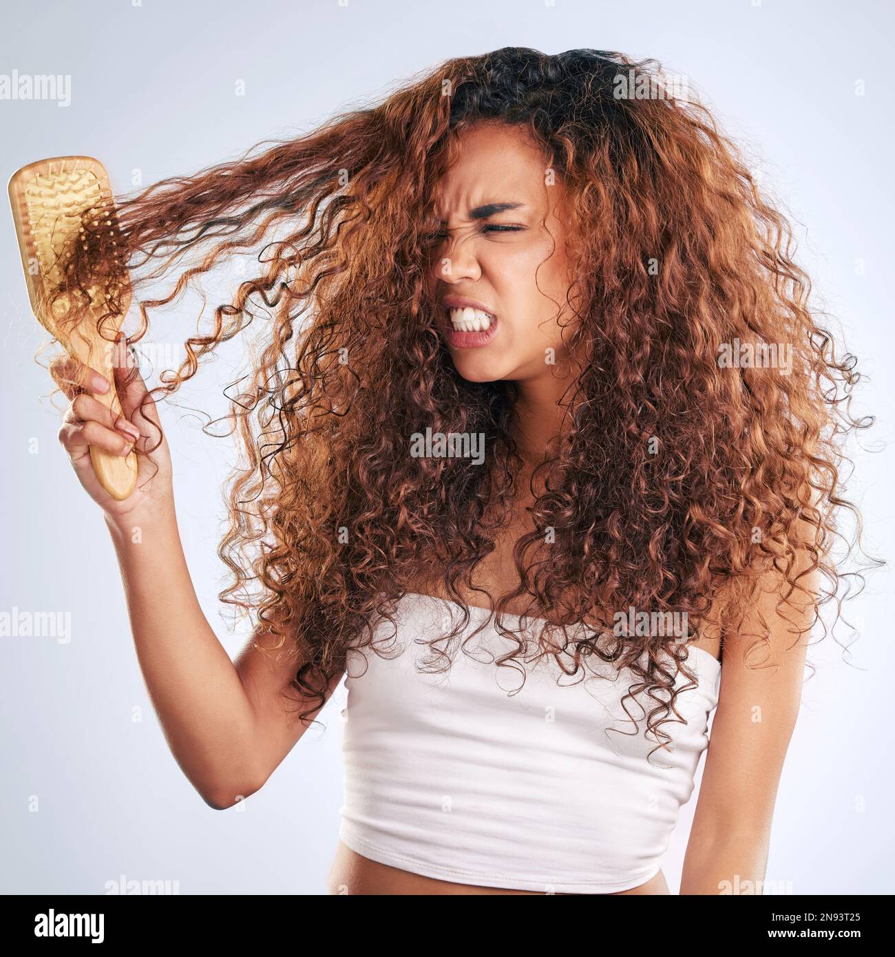 Come on. an attractive young woman struggling with knotted hair in ...