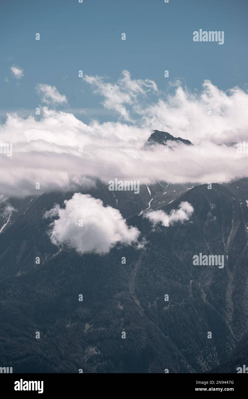 A scenic view of the mountain peaks touching the clouds under blue sky on a sunny day Stock ...