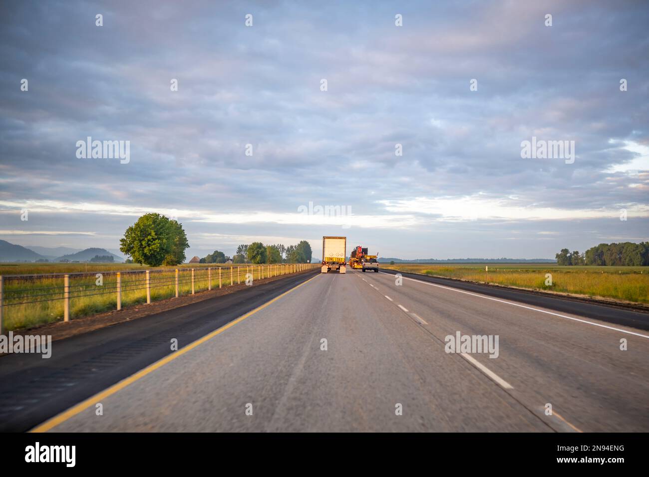 Two big rigs semi trucks with loaded semi trailers and long load and ...