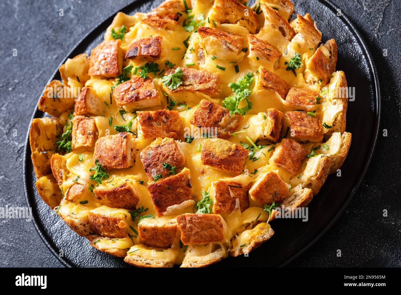 cheesy garlic crusty bread, pull apart whole round bread on black ...