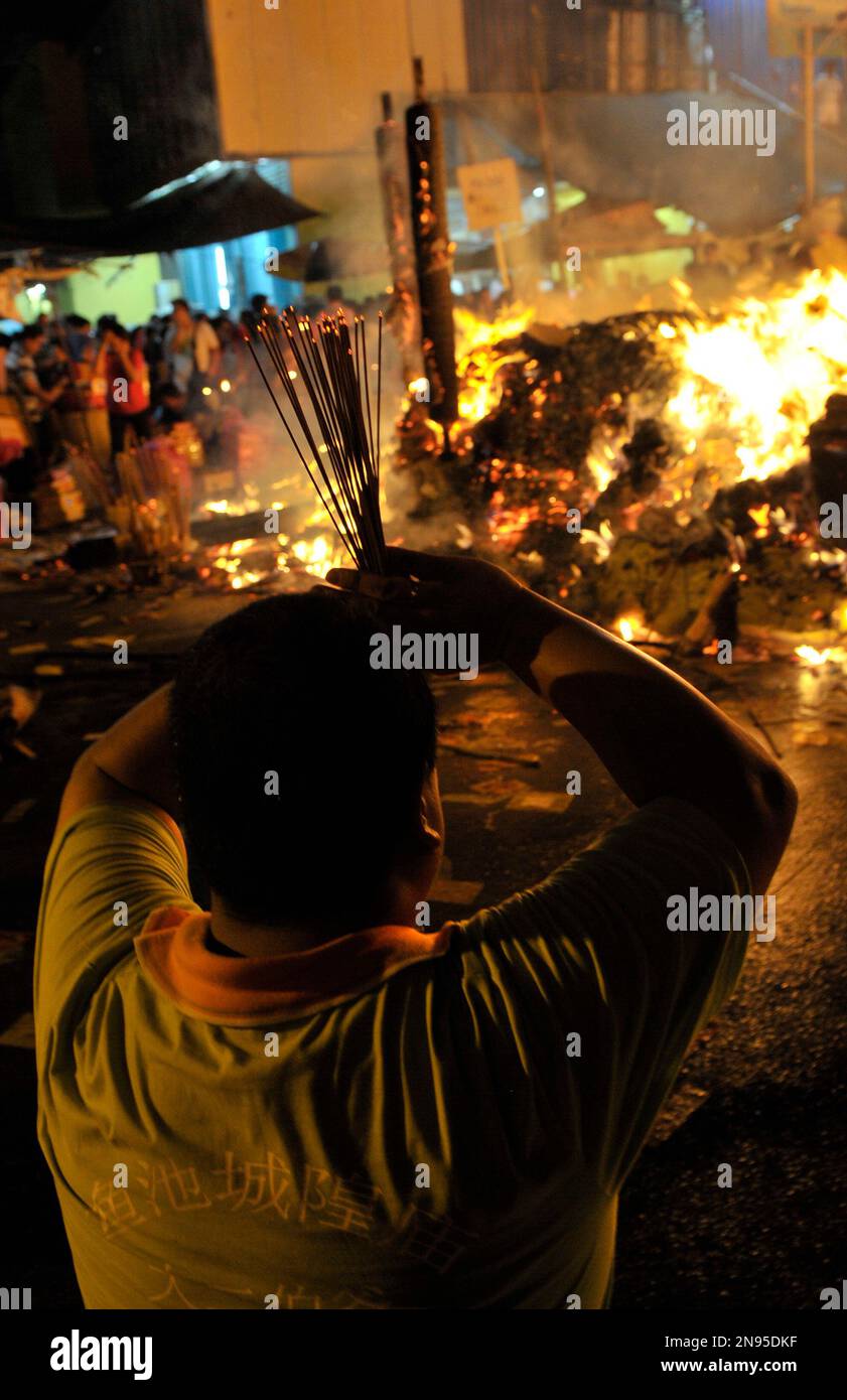 Ethnic Chinese burn joss sticks as a giant paper statue of the Chinese ...