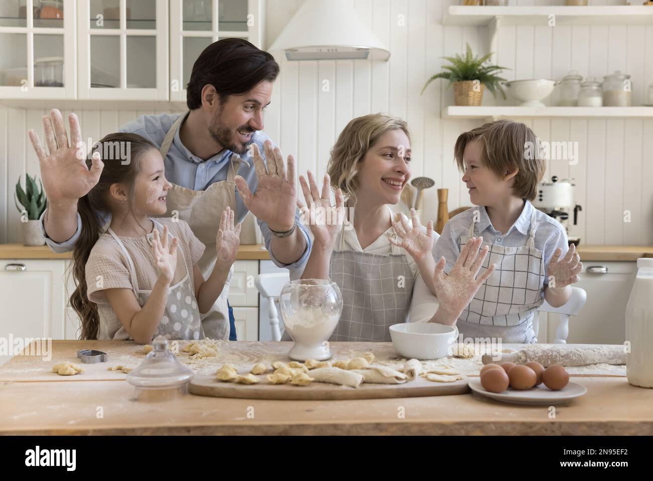 Joyful parents and two happy kids in aprons baking together Stock Photo ...