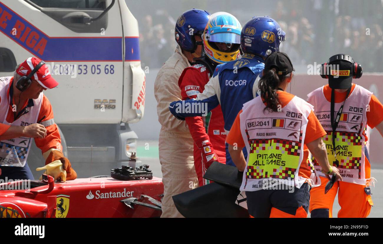 Ferrari driver Fernando Alonso of Spain is helped by a doctor after ...