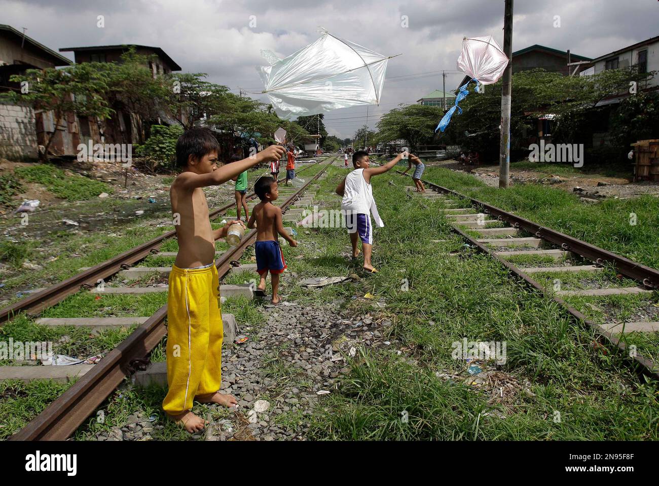 Filipino children fly kites along the railroads in suburban Manila ...