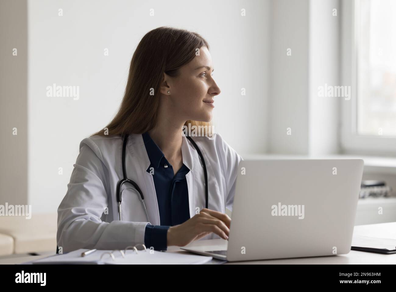 Dreamy happy beautiful young doctor women working at laptop computer ...