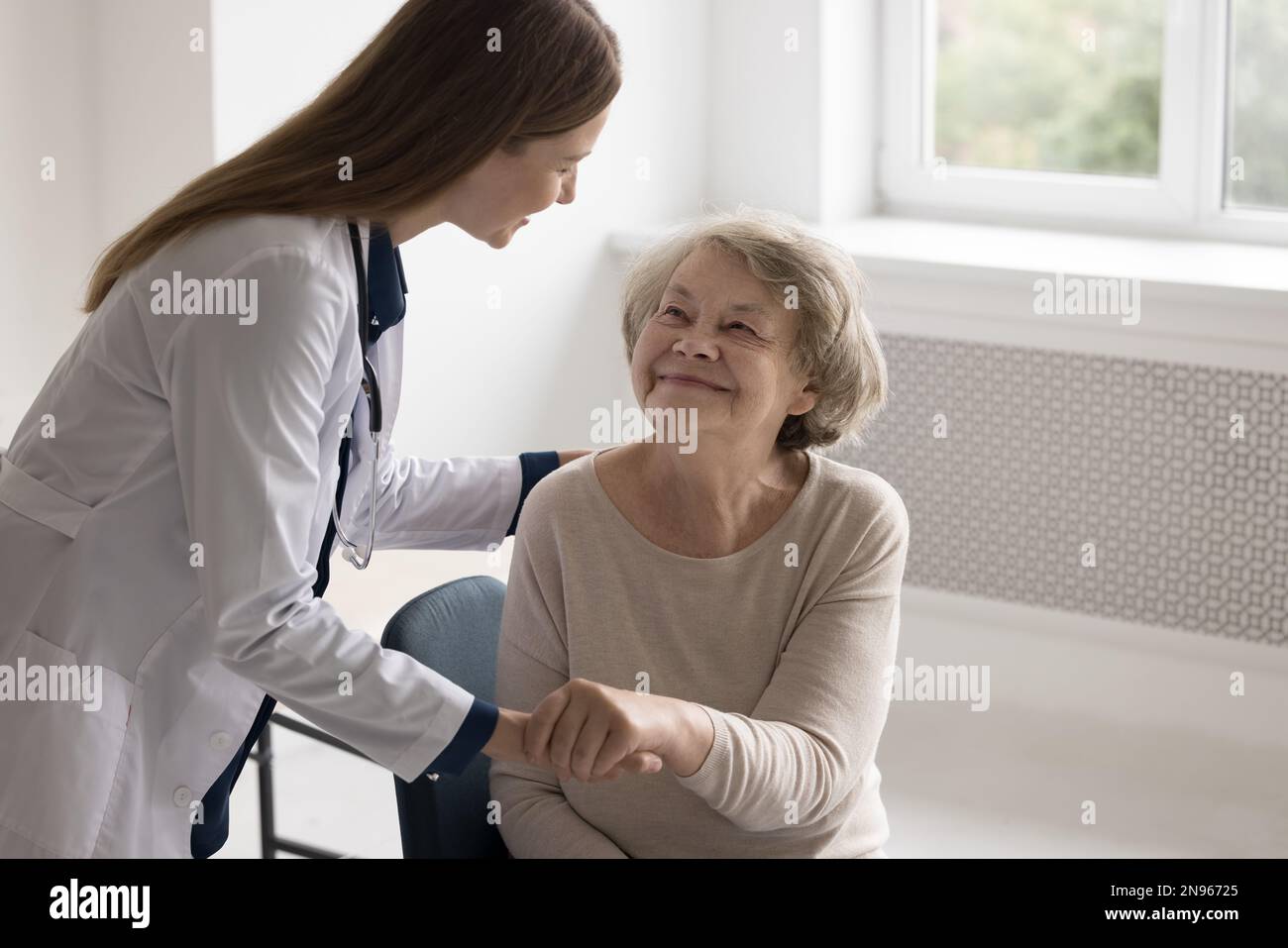 Positive empathetic doctor woman giving comfort to elderly patient ...