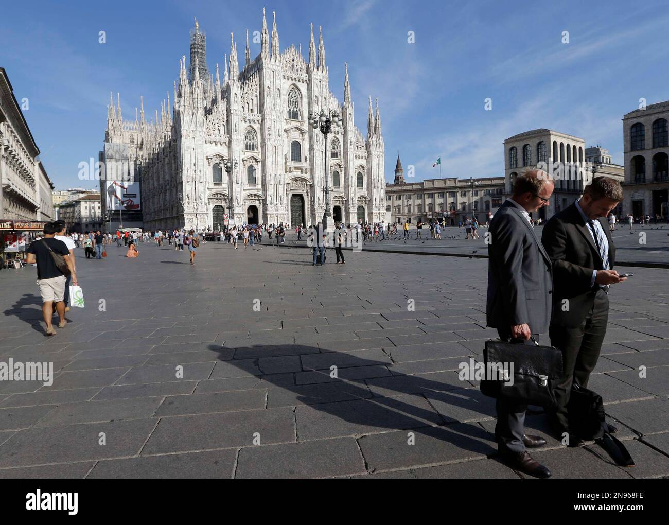 Two men walk in front of the Duomo gothic cathedral, in Milan, Italy ...
